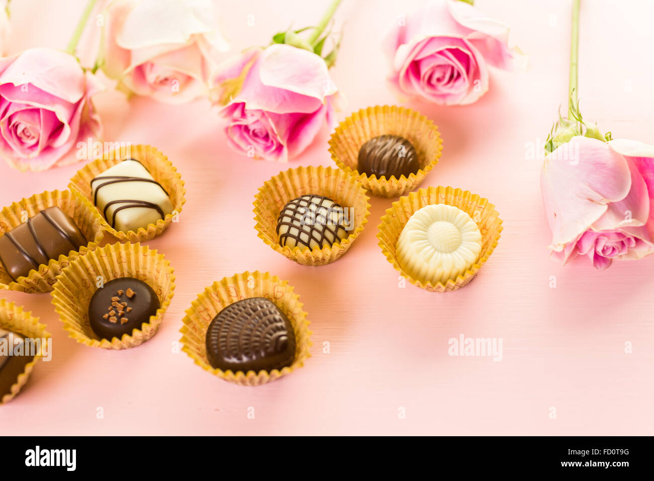 Assorted chocolates with pink roses on pink background Stock Photo - Alamy