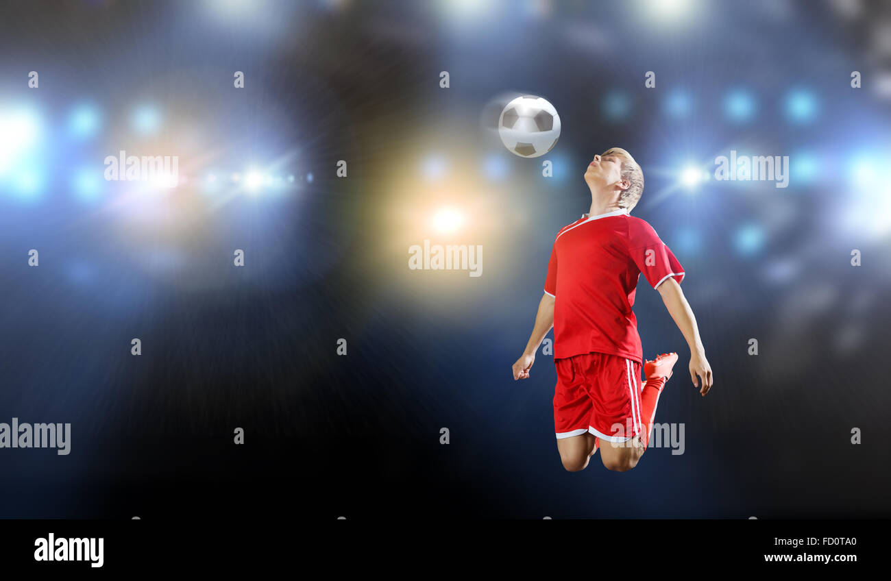 Young football player on stadium kicking ball in jump hi-res stock ...