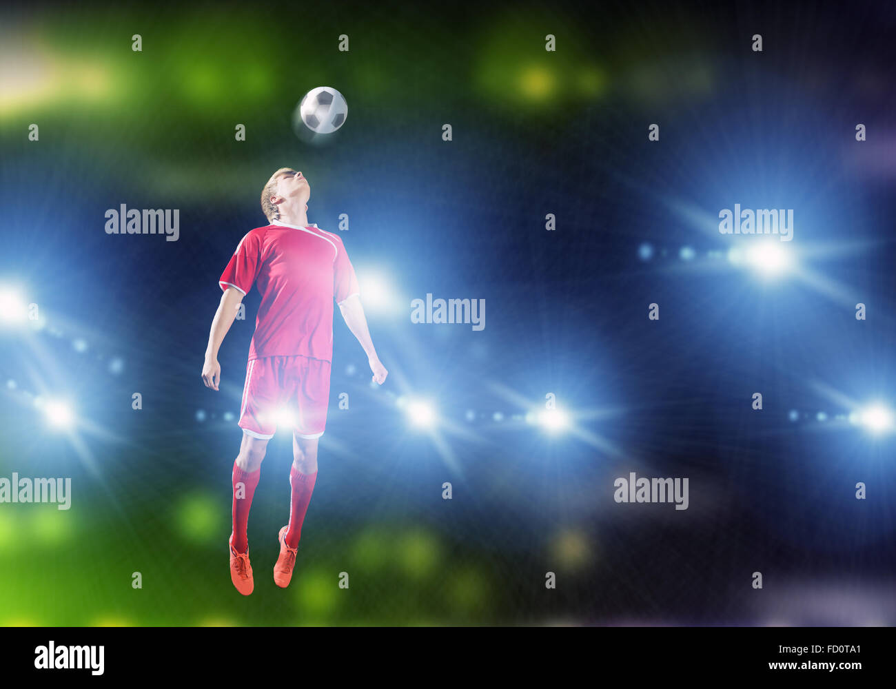 Young football player on stadium kicking ball with head in jump Stock ...