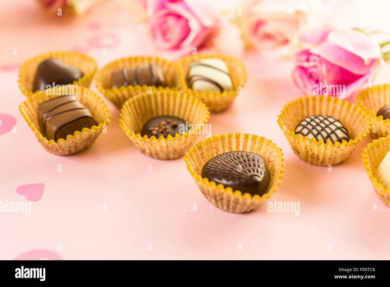 Assorted chocolates with pink roses on pink background Stock Photo - Alamy