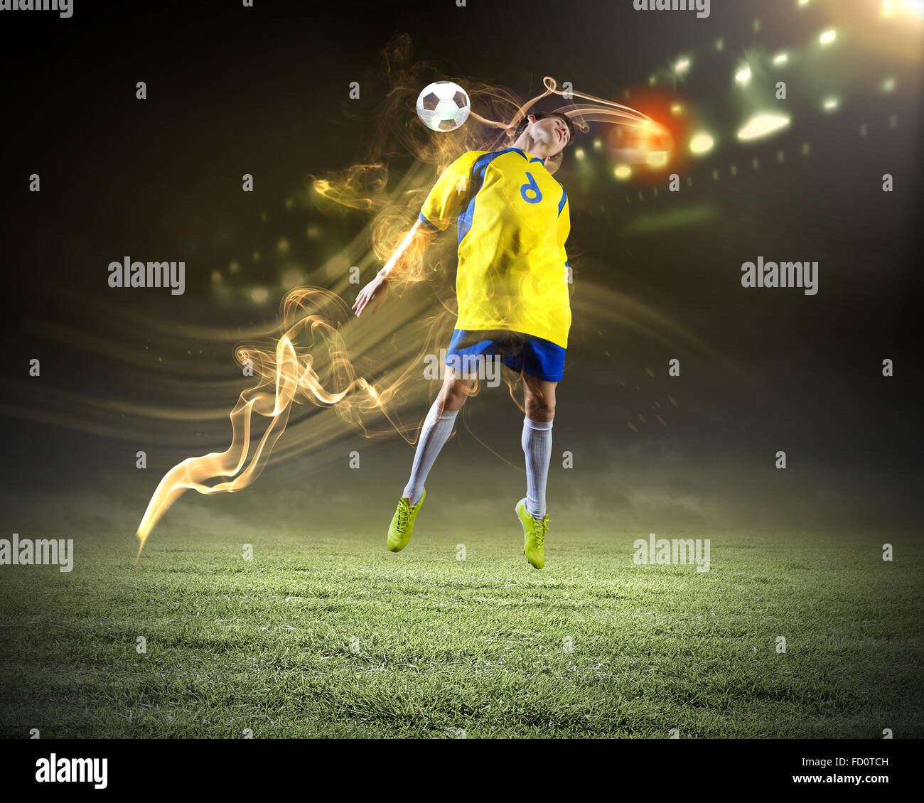 Young football player on stadium kicking ball with head in jump Stock ...