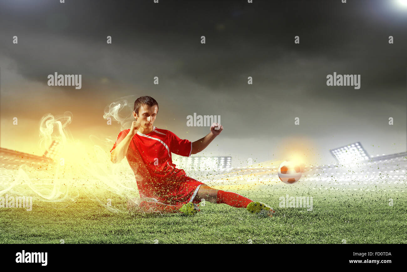 Young football player on stadium doing slide tackle Stock Photo - Alamy
