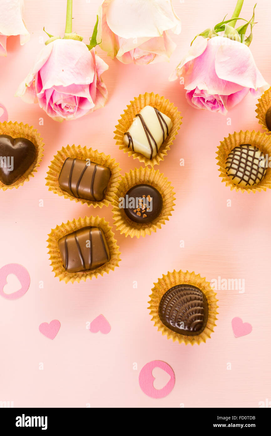 Assorted chocolates with pink roses on pink background Stock Photo - Alamy