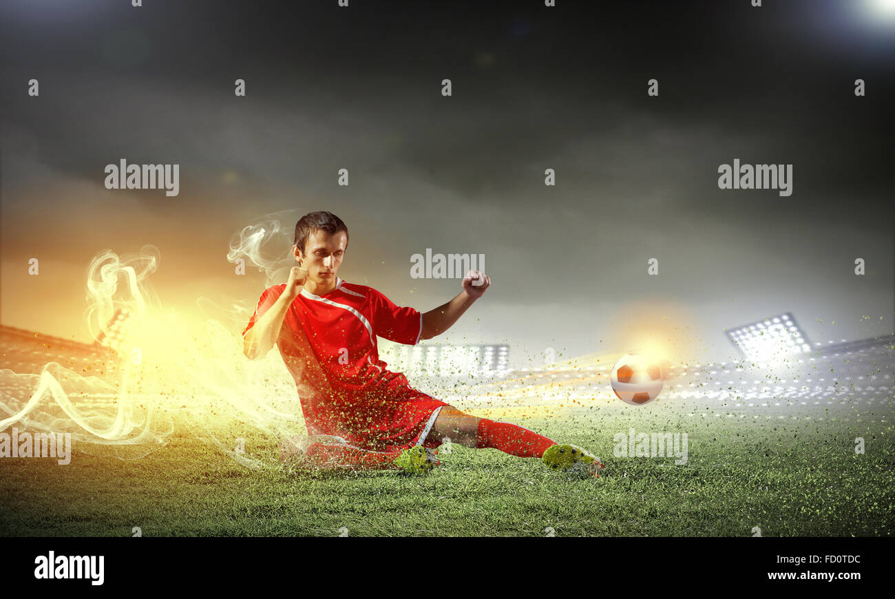 Young football player on stadium doing slide tackle Stock Photo - Alamy
