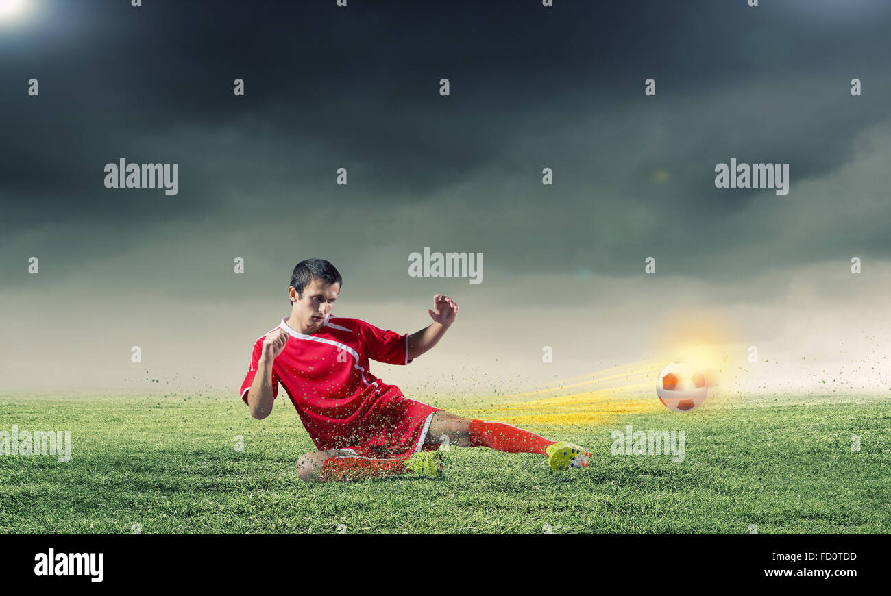 Young football player on stadium doing slide tackle Stock Photo - Alamy