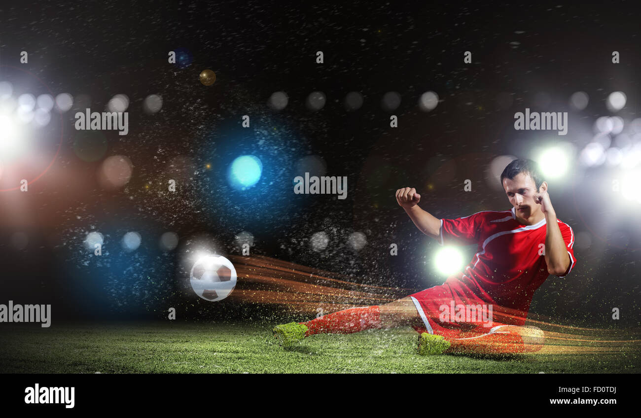 Young football player on stadium doing slide tackle Stock Photo - Alamy