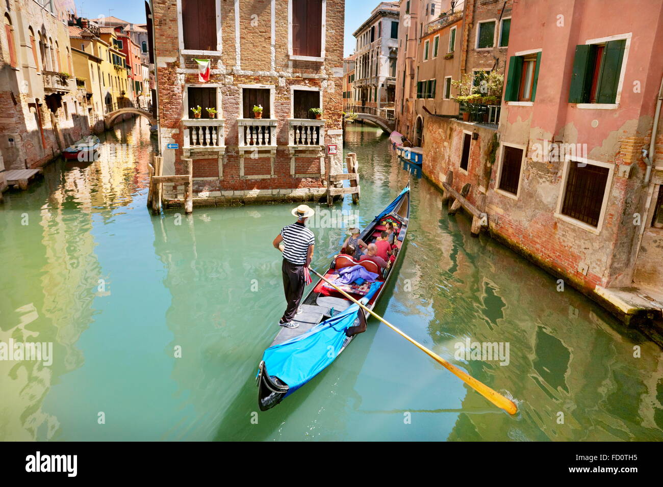 Gondolier with his gondola in one of the numerous canals Venice, Veneto ...