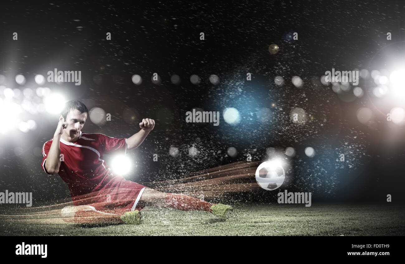 Young football player on stadium doing slide tackle Stock Photo - Alamy