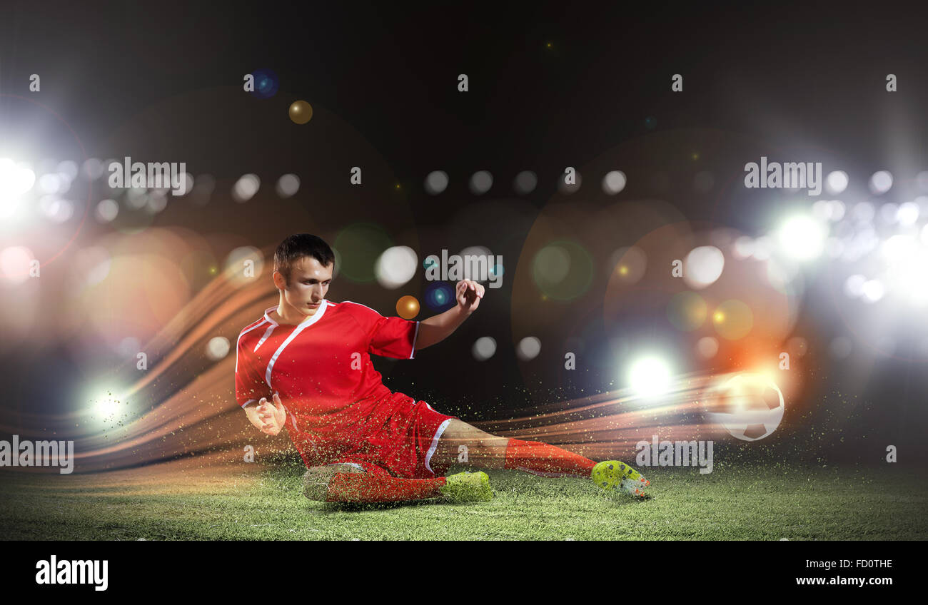 Young football player on stadium doing slide tackle Stock Photo - Alamy