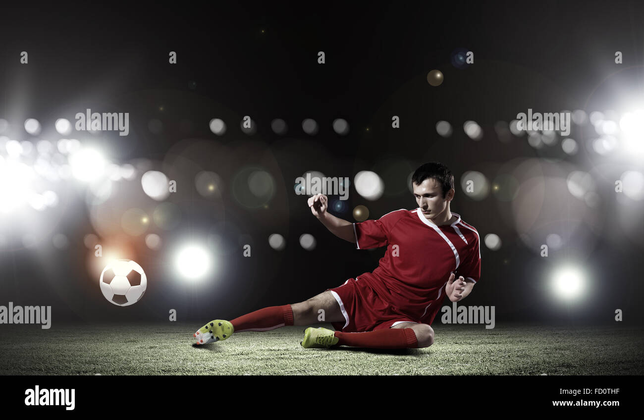 Young football player on stadium doing slide tackle Stock Photo - Alamy