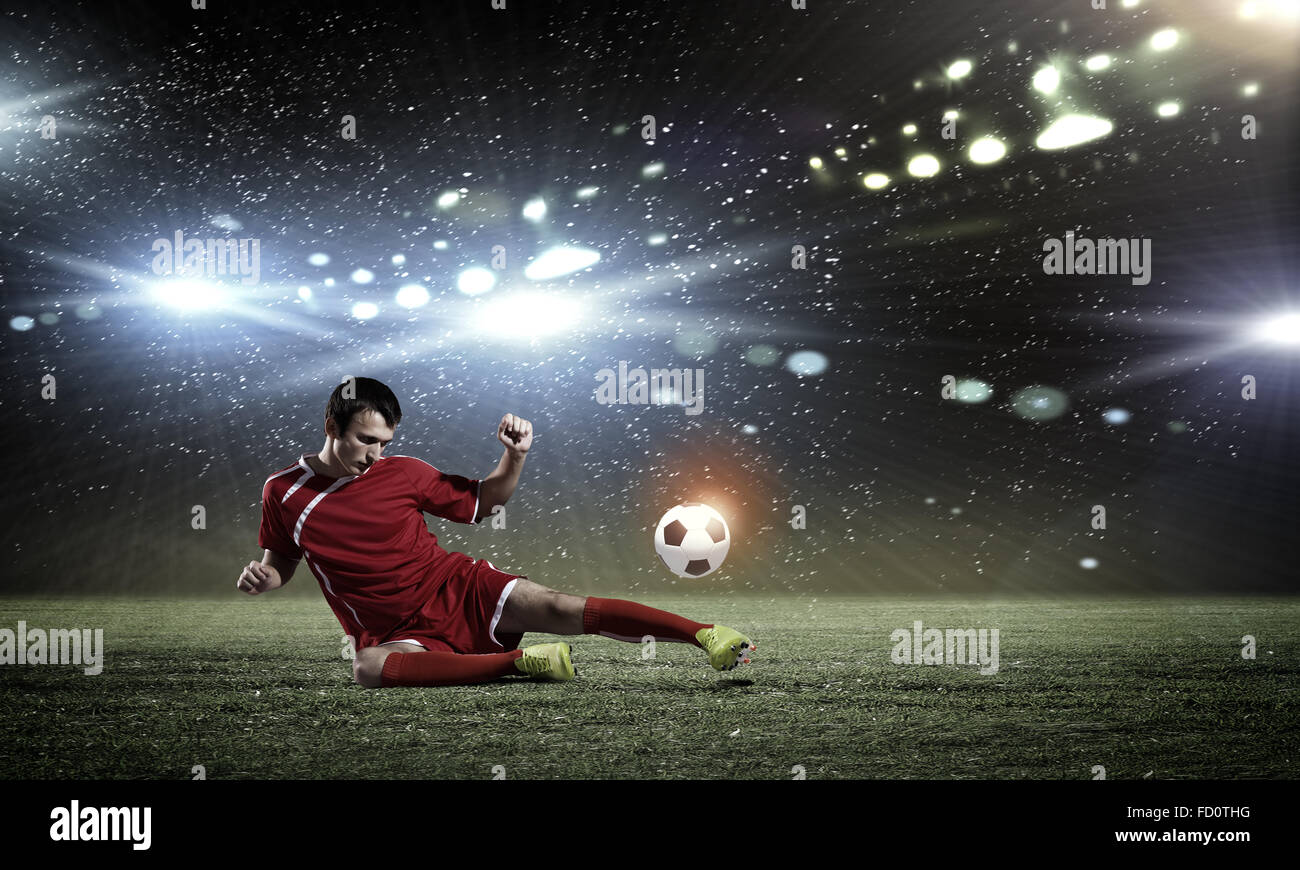 Young football player on stadium doing slide tackle Stock Photo - Alamy