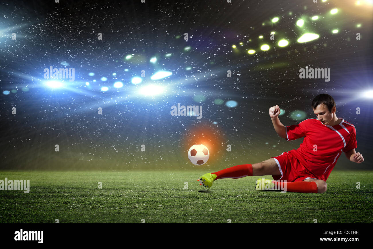 Young football player on stadium doing slide tackle Stock Photo - Alamy