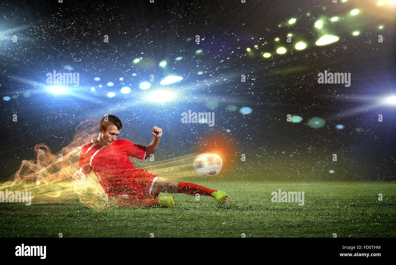 Young football player on stadium doing slide tackle Stock Photo - Alamy