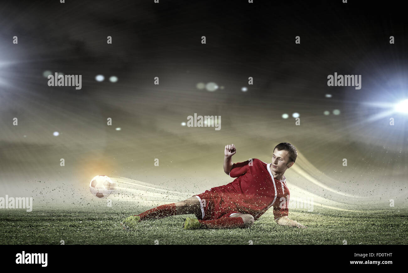 Young football player on stadium doing slide tackle Stock Photo - Alamy