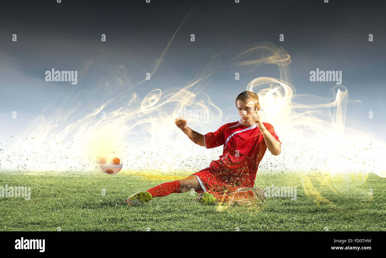 Young football player on stadium doing slide tackle Stock Photo - Alamy