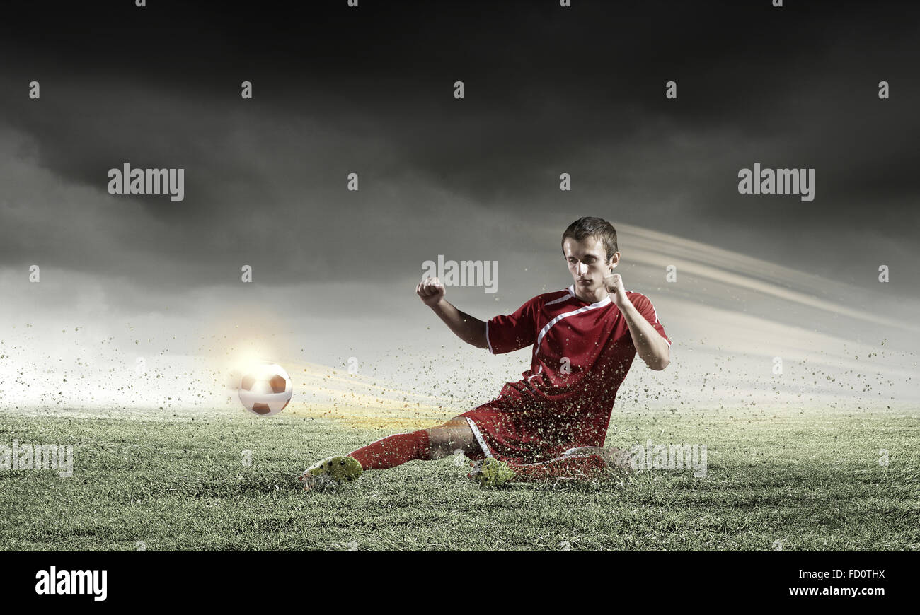 Young football player on stadium doing slide tackle Stock Photo - Alamy