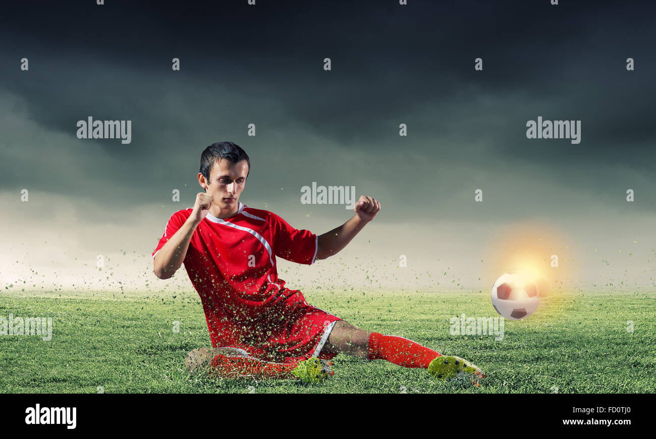 Young football player on stadium doing slide tackle Stock Photo - Alamy