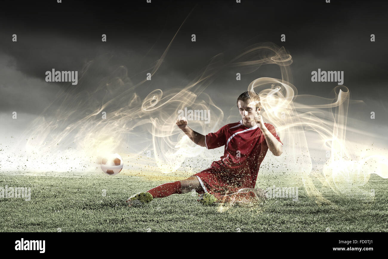 Young football player on stadium doing slide tackle Stock Photo - Alamy