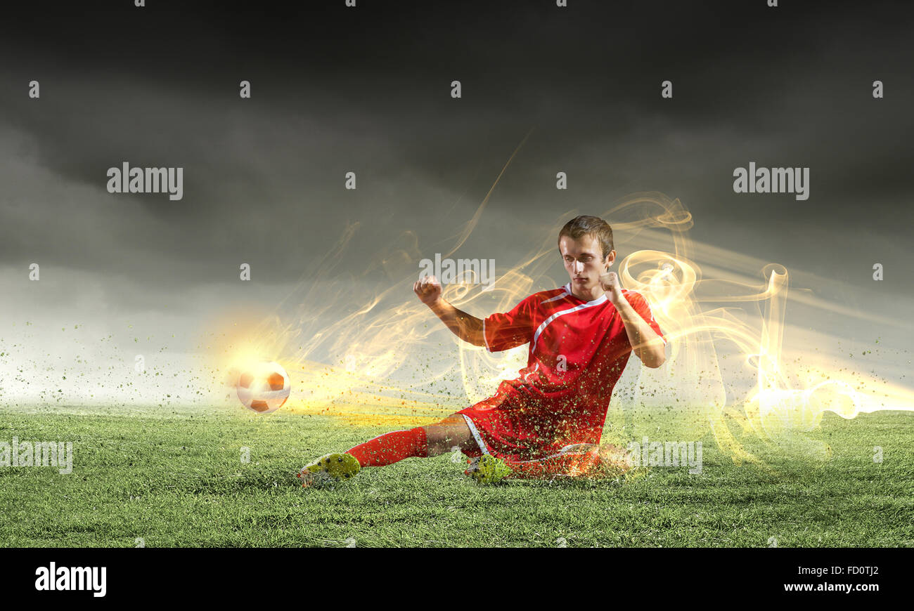 Young football player on stadium doing slide tackle Stock Photo - Alamy