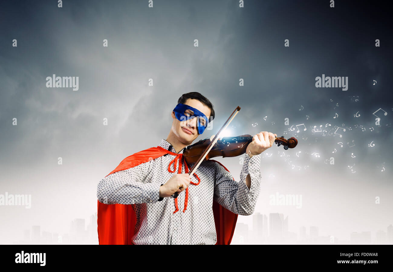 Young man in superhero costume playing violin Stock Photo - Alamy