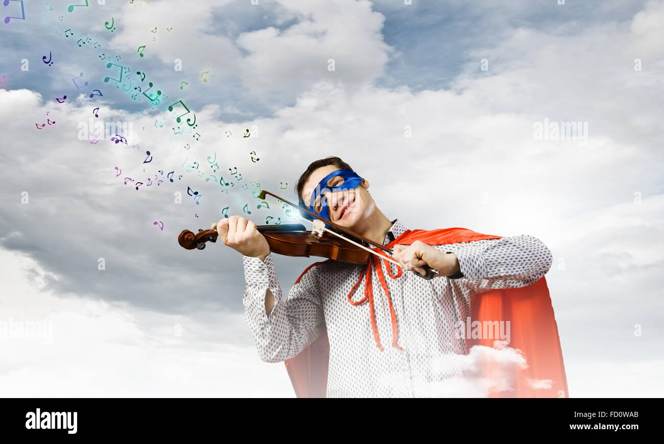 Young man in superhero costume playing violin Stock Photo - Alamy