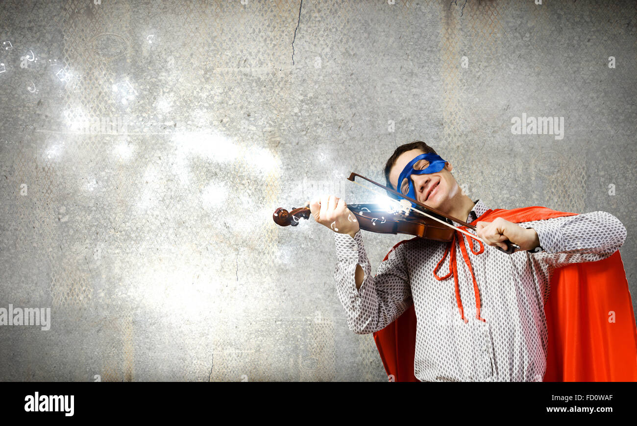 Young man in superhero costume playing violin Stock Photo - Alamy