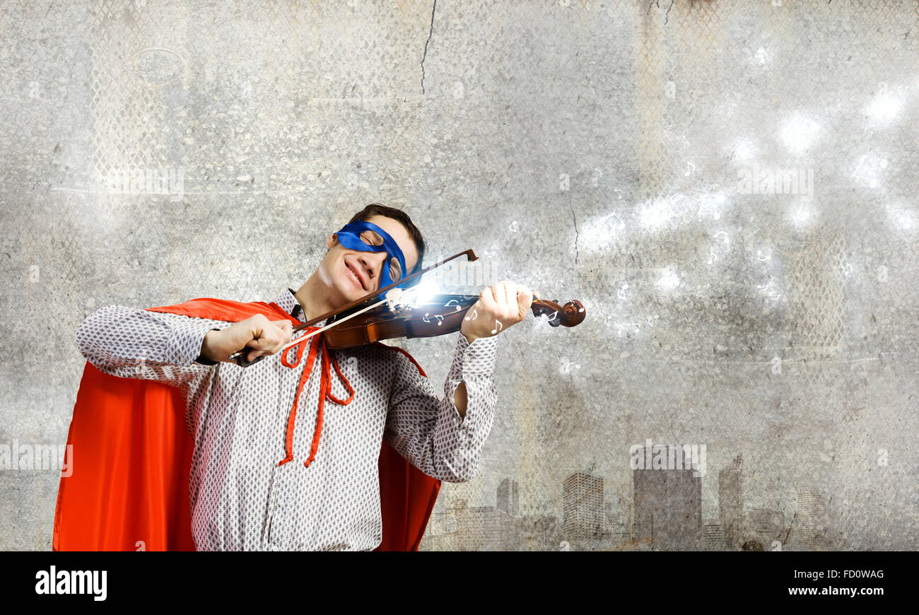 Young man in superhero costume playing violin Stock Photo - Alamy