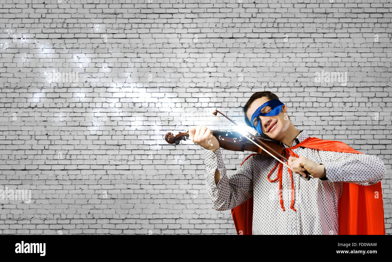 Young man in superhero costume playing violin Stock Photo - Alamy