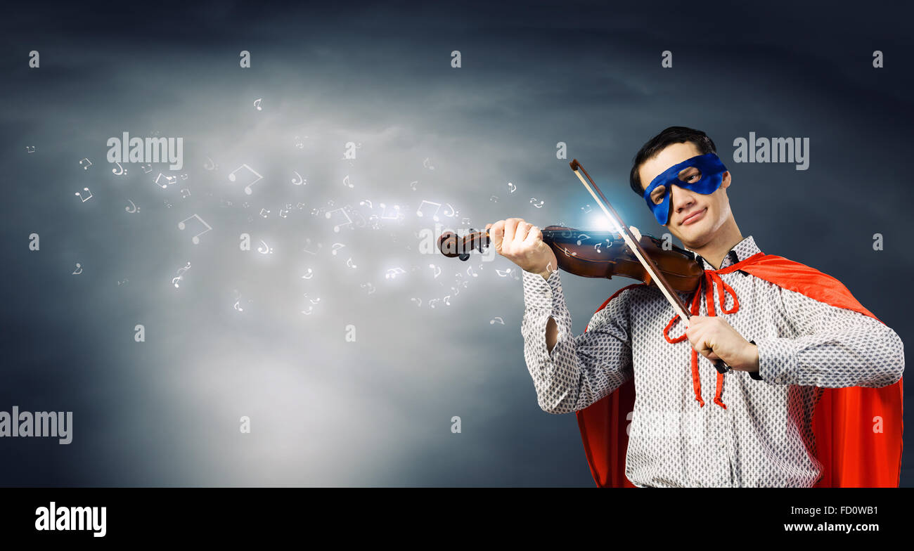 Young man in superhero costume playing violin Stock Photo - Alamy