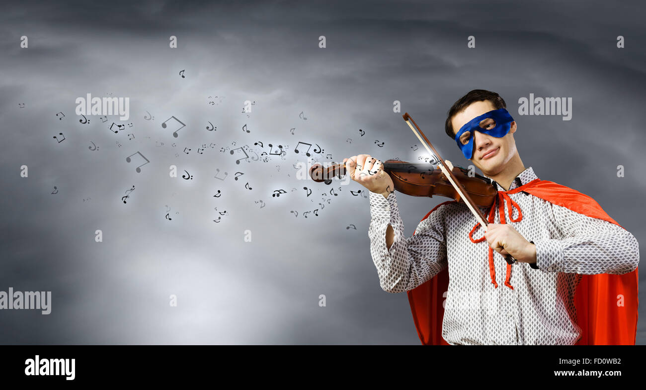Young man in superhero costume playing violin Stock Photo - Alamy