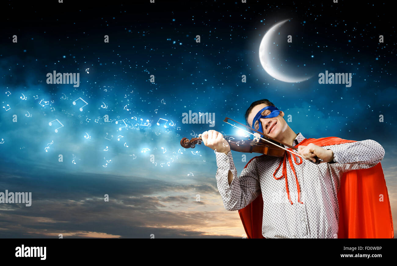 Young man in superhero costume playing violin Stock Photo - Alamy