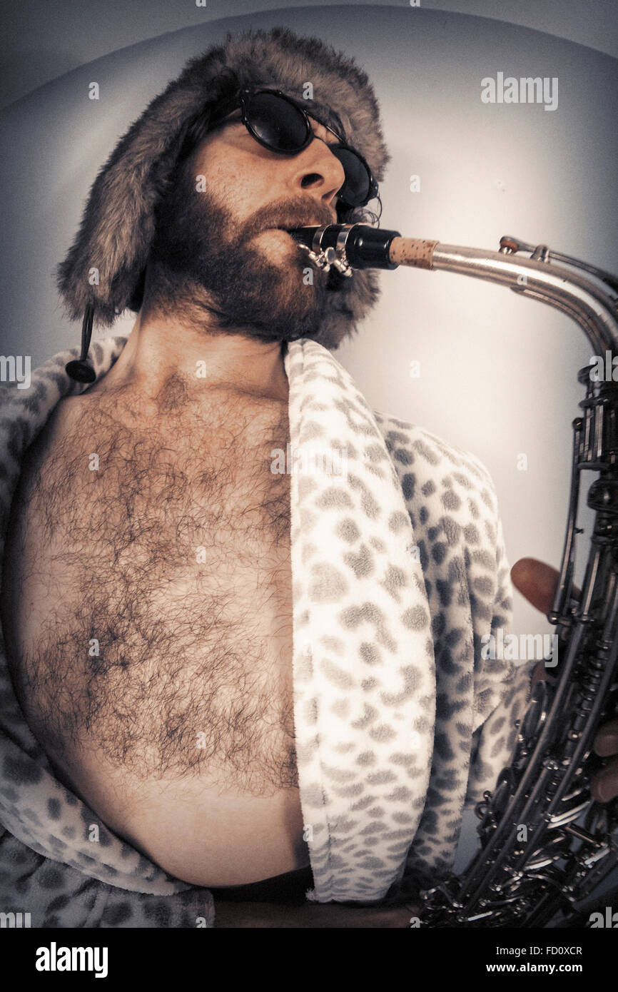 Bearded hipster plays jazz saxophone in leopard print bathrobe taken ...