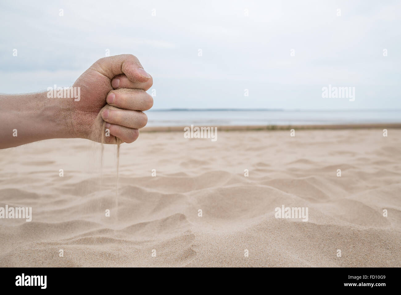 The sand runs through clenched fist. On the background - calm sea Stock ...