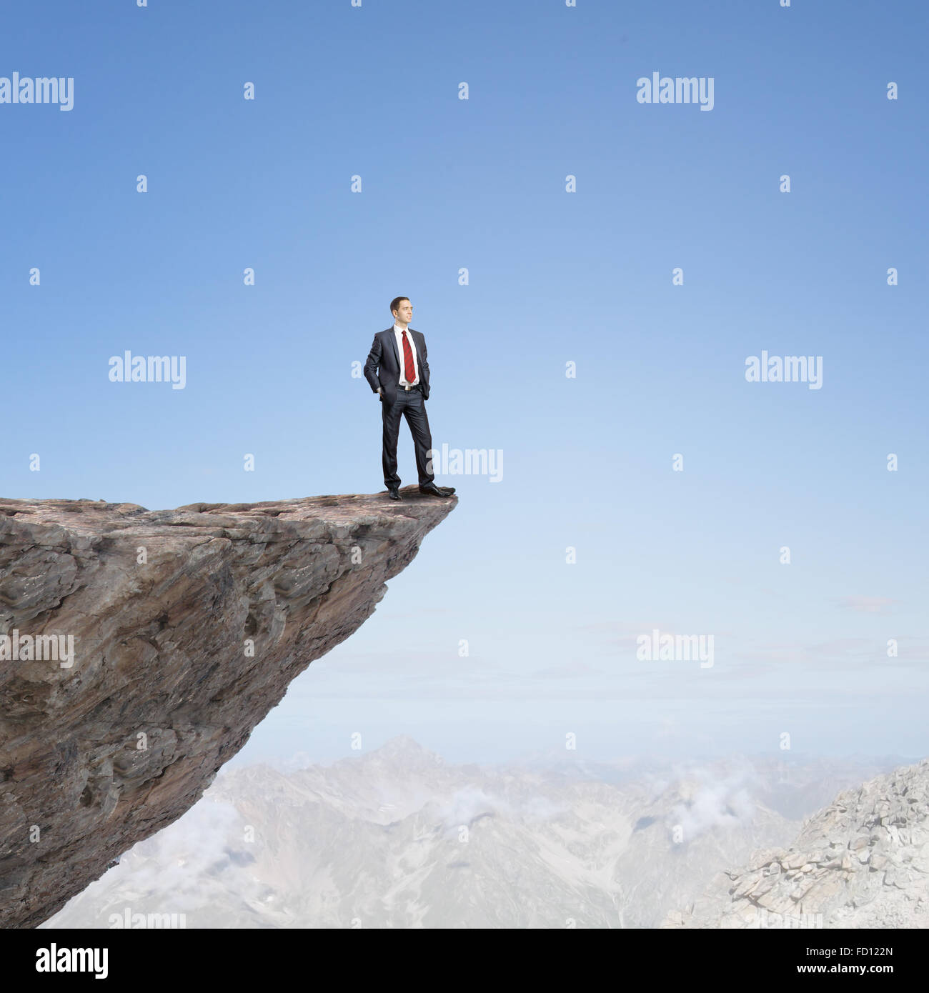 Young businessman standing on edge of rock mountain Stock Photo - Alamy