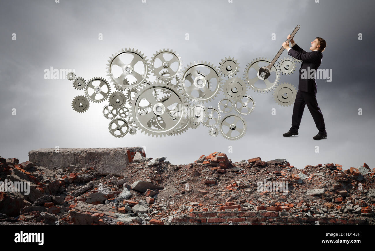 Young businessman fixing gears mechanism with wrench Stock Photo - Alamy