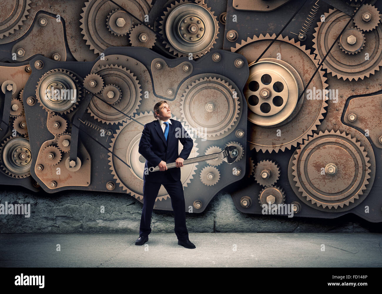 Young businessman fixing gears mechanism with wrench Stock Photo - Alamy