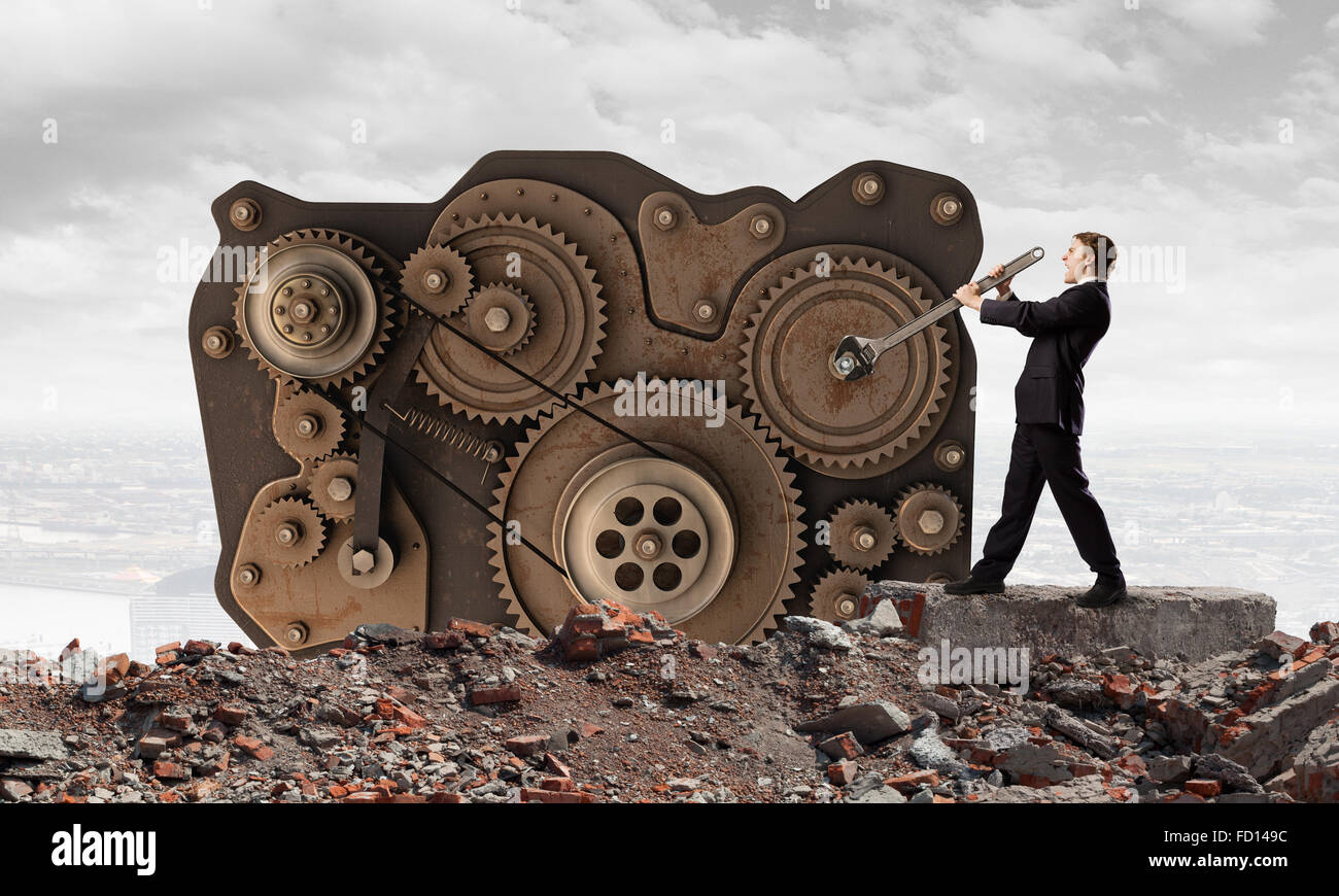 Young businessman fixing gears mechanism with wrench Stock Photo - Alamy