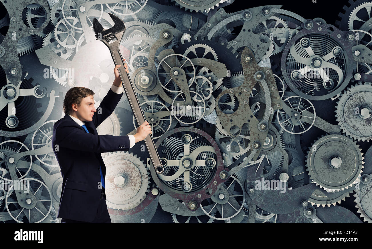 Young businessman fixing gears mechanism with wrench Stock Photo - Alamy