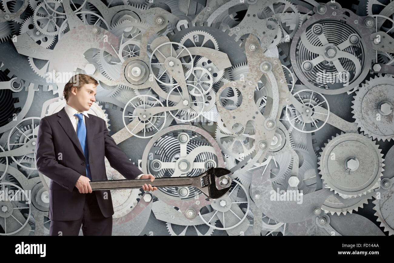 Young businessman fixing gears mechanism with wrench Stock Photo - Alamy