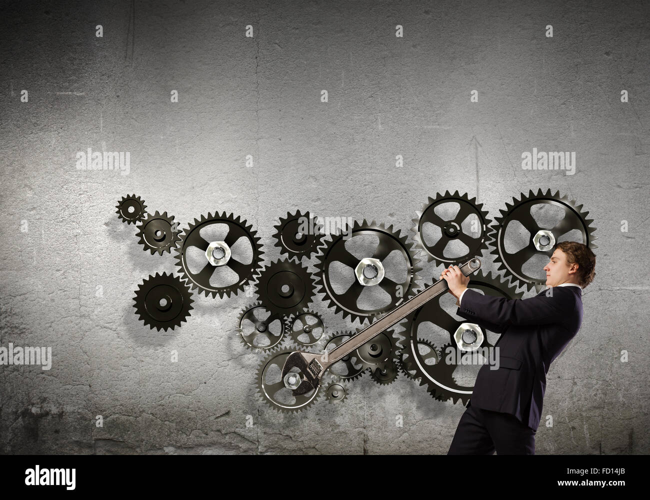 Young businessman fixing gears mechanism with wrench Stock Photo - Alamy