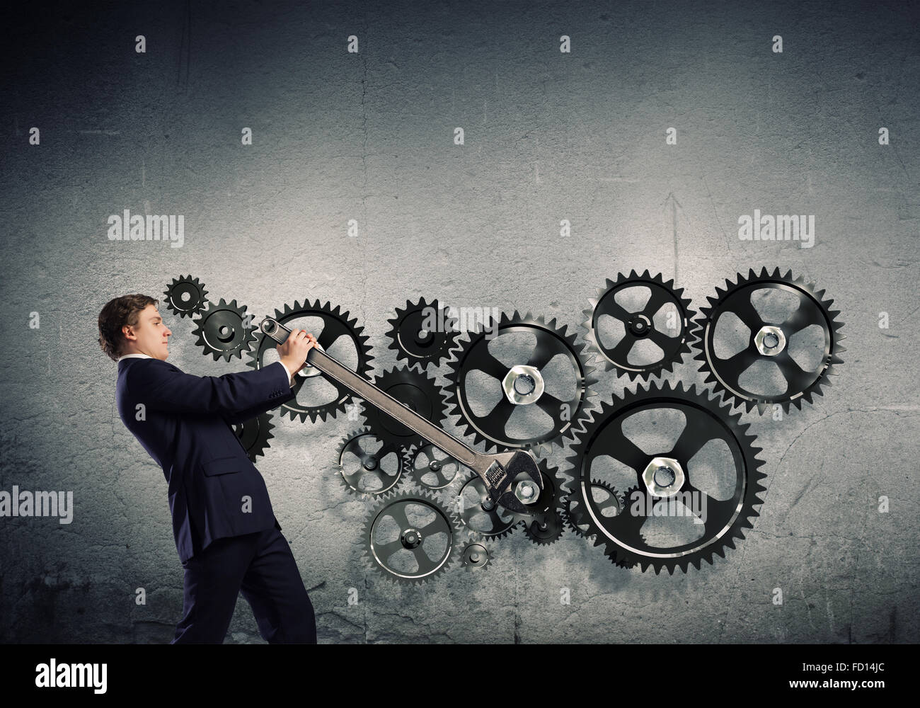 Young businessman fixing gears mechanism with wrench Stock Photo - Alamy