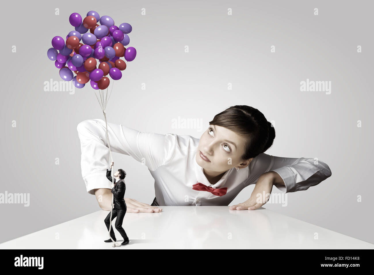 Businesswoman looking from under the table at businessman miniature ...