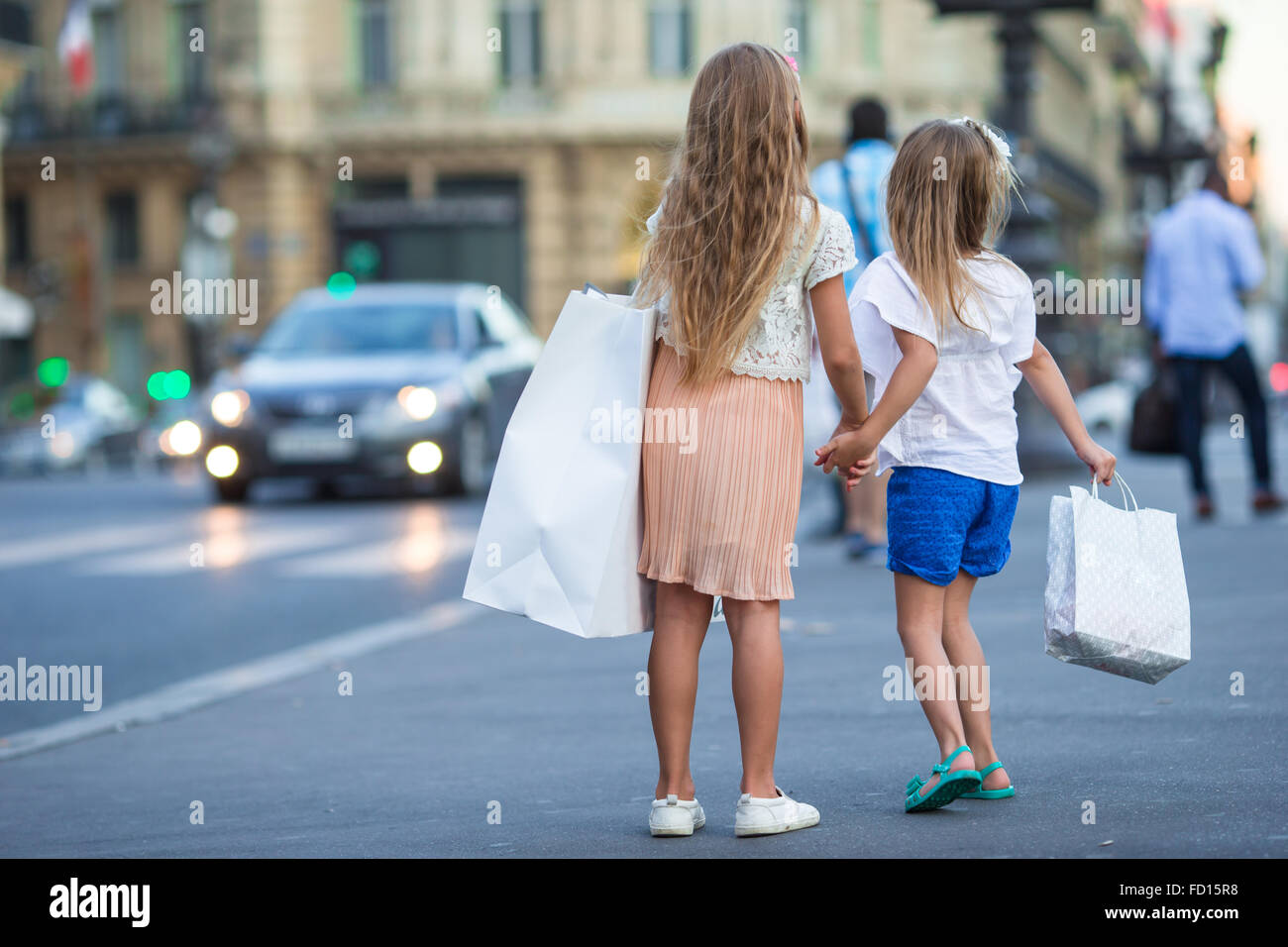 Adorable fashion little girls with packages outdoors in European city ...