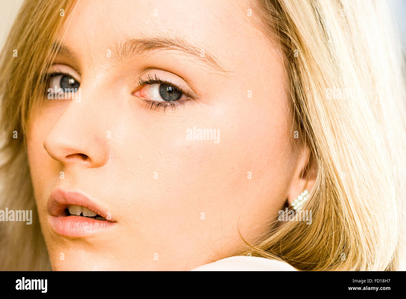 Blonde, blue eyed teenage girls, close up of face, as it turns to look ...