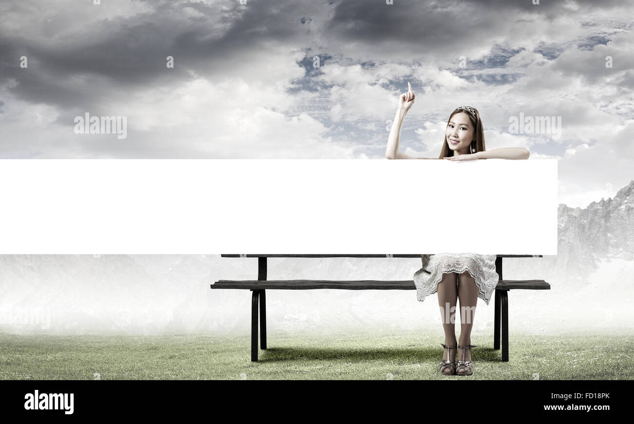 Young asian woman sitting on bench with blank banner Stock Photo - Alamy