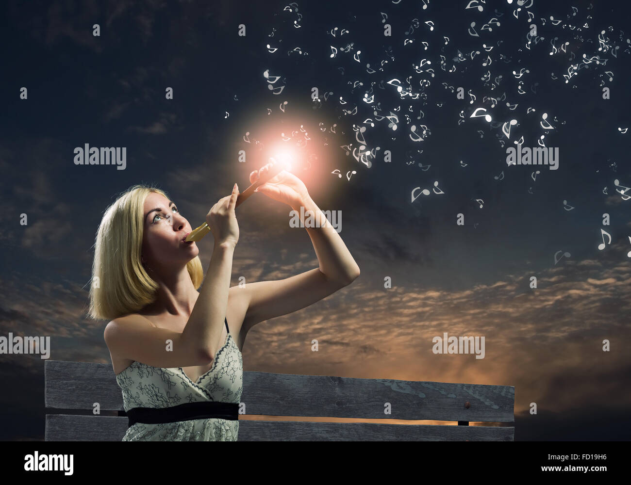 Young woman sitting on bench and playing fife Stock Photo - Alamy