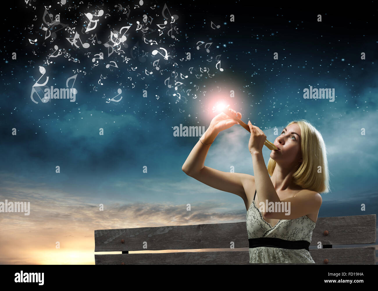 Young woman sitting on bench and playing fife Stock Photo - Alamy