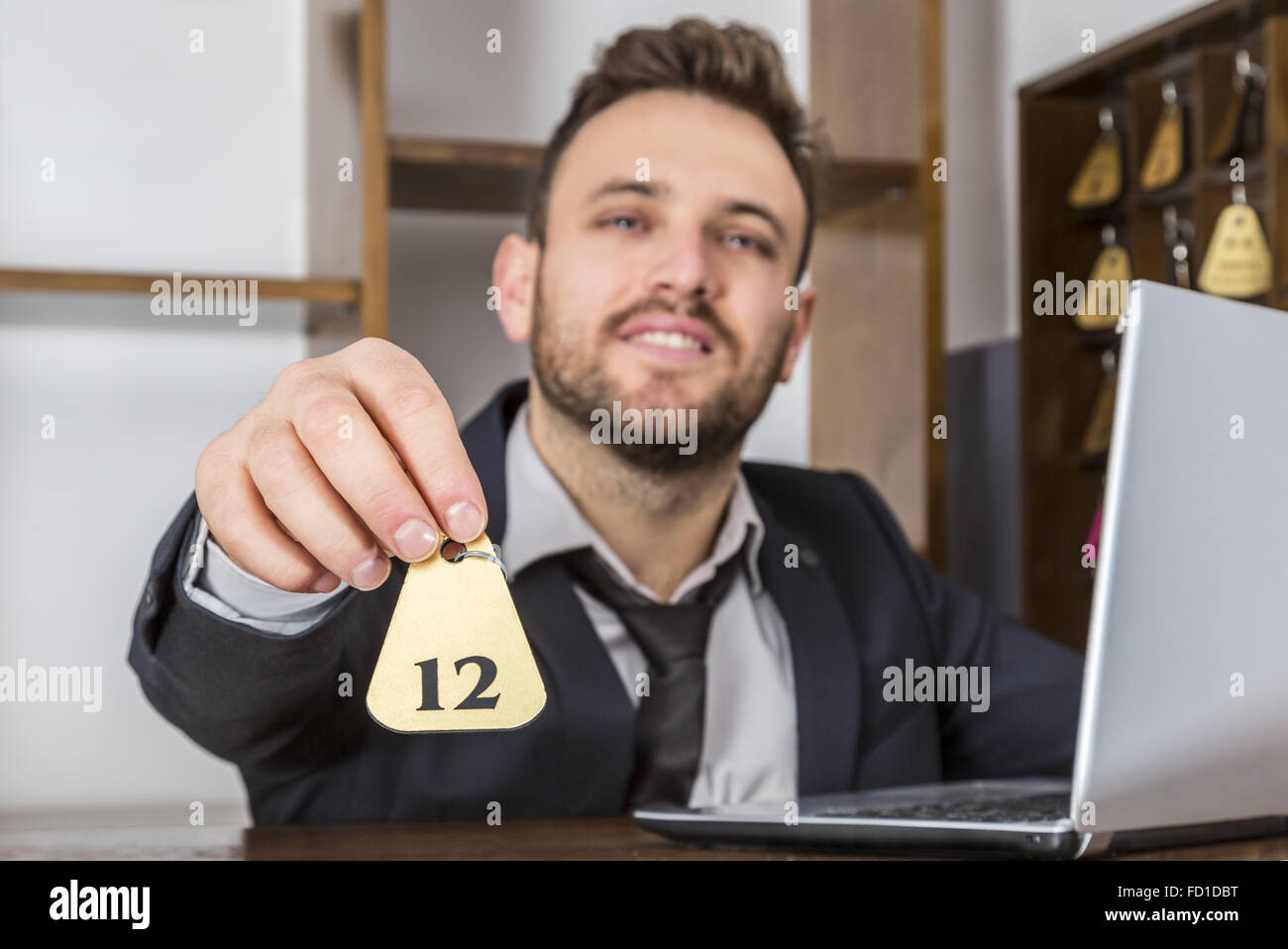 Image of a receptionist at his desk giving the key to a client ...