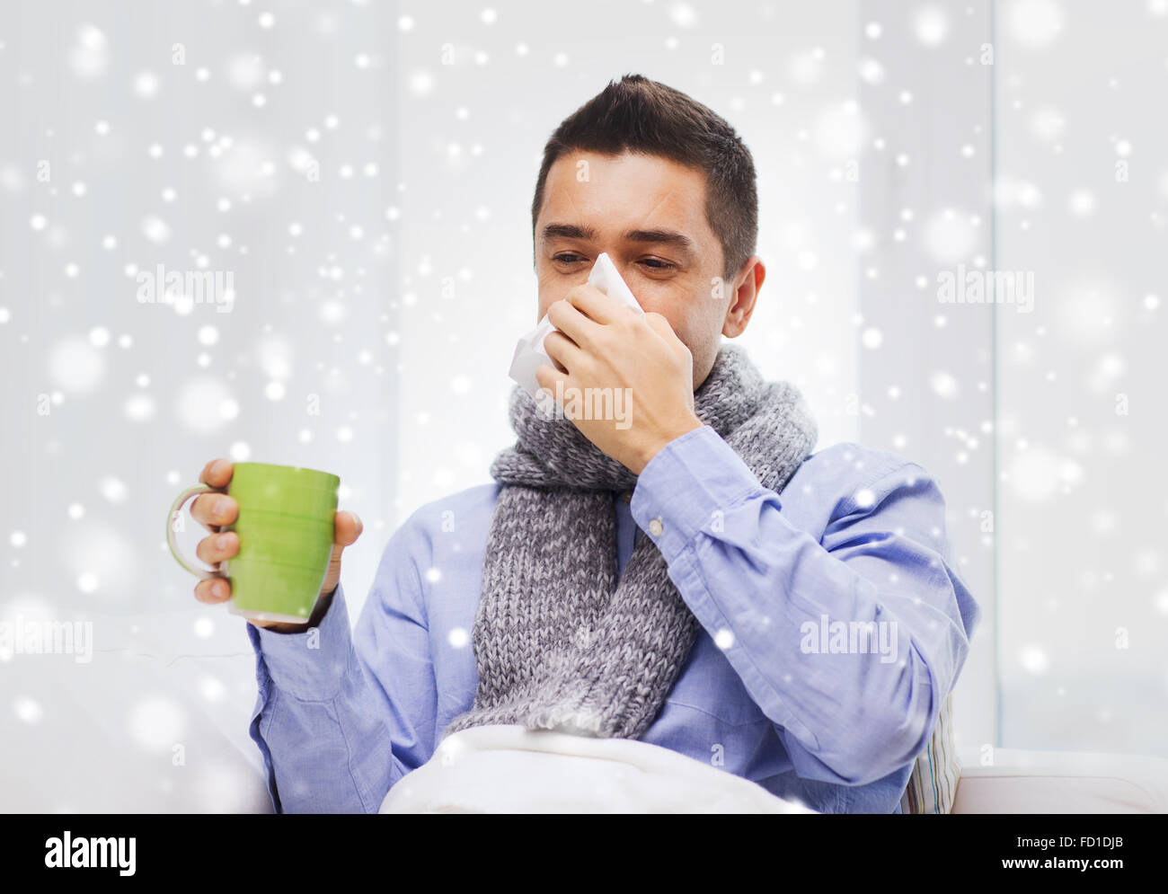 ill man with flu drinking tea and blowing nose Stock Photo - Alamy