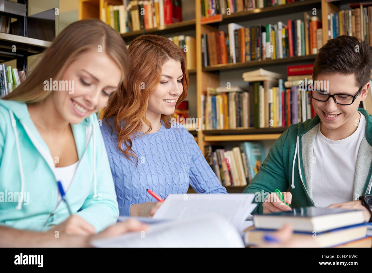 happy students writing to notebooks in library Stock Photo - Alamy